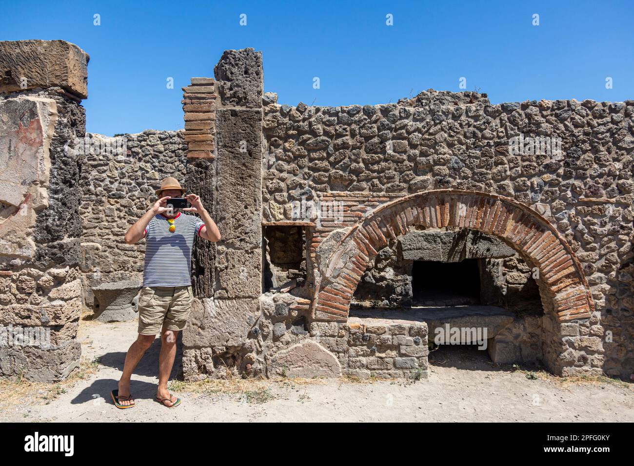 A man takes a picture of a brick oven in a ruins in the ancient city of ...