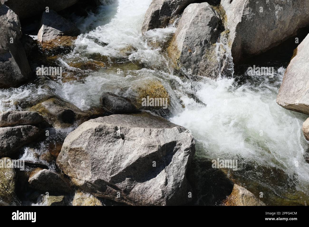 A cascading stream of crystal clear water flowing down a bed of smooth ...