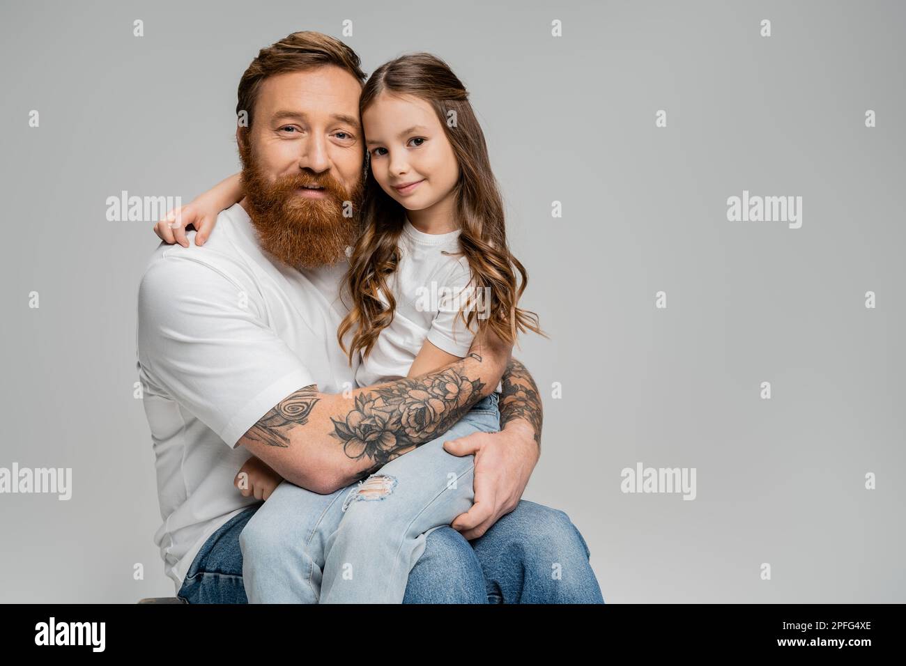 Bearded man hugging smiling daughter in t-shirt and jeans isolated on ...
