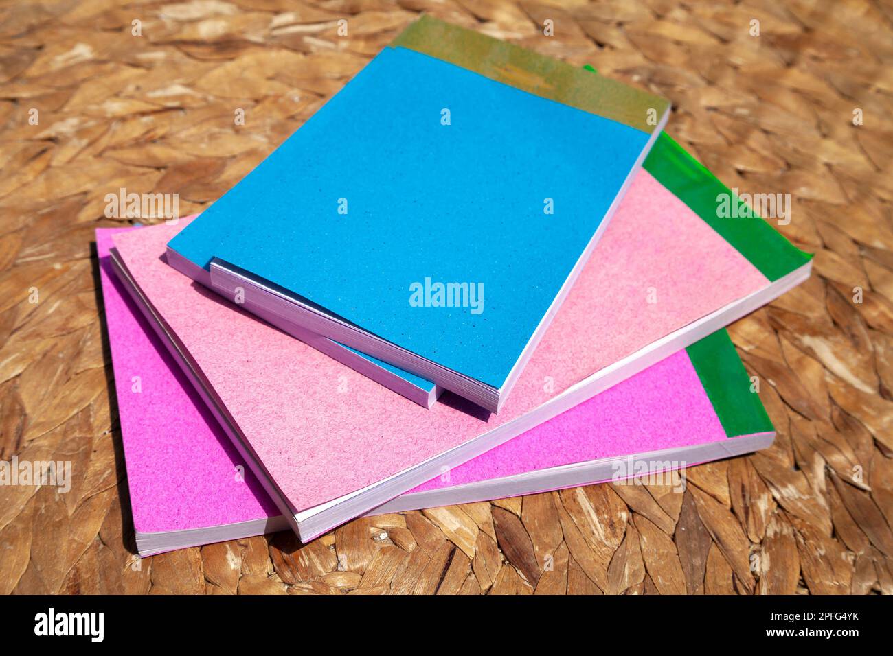Several cheap notepads of various colors and sizes stacked on a wooden ...