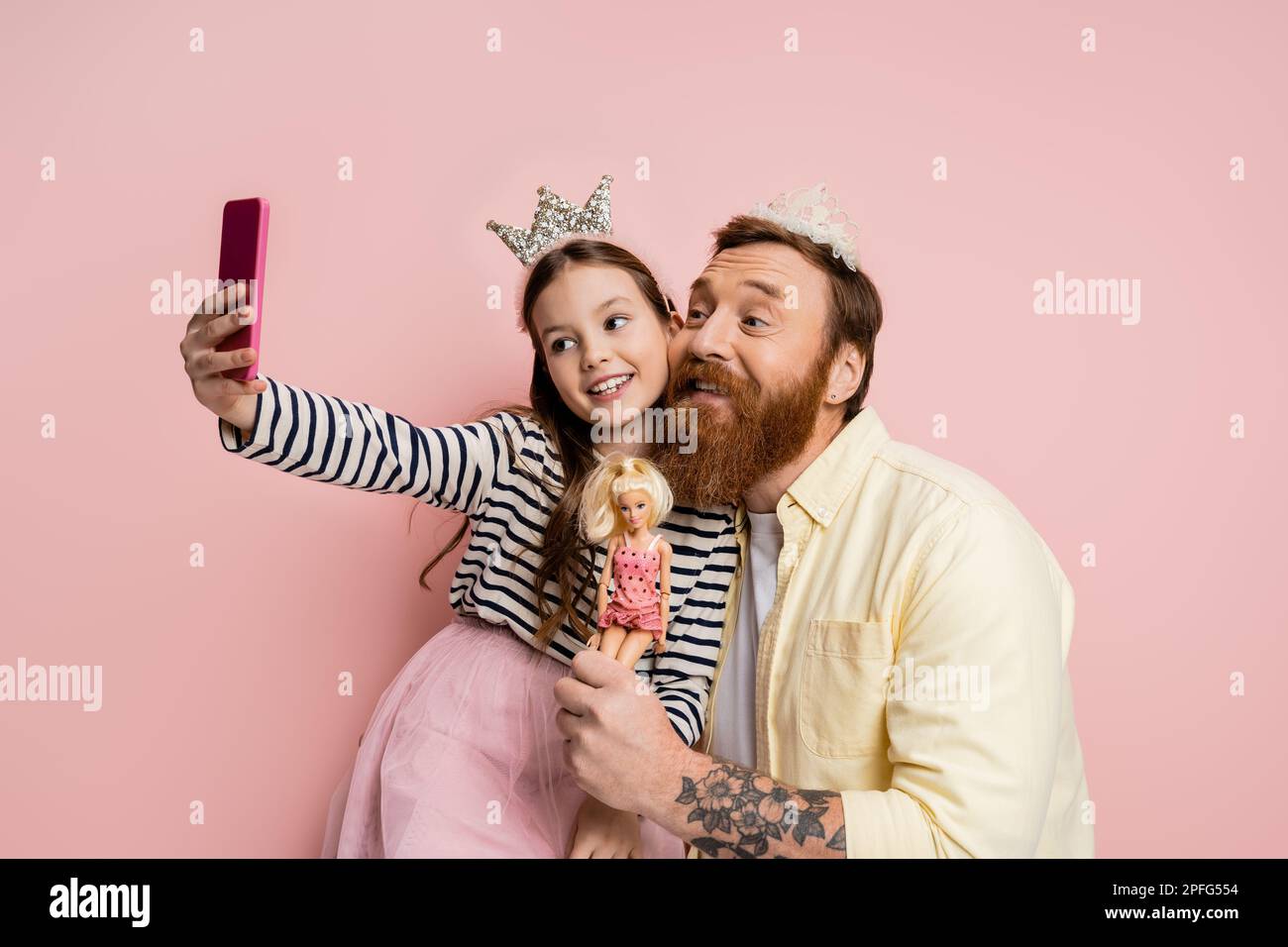 Cheerful preteen girl taking selfie with father with crown headband ...