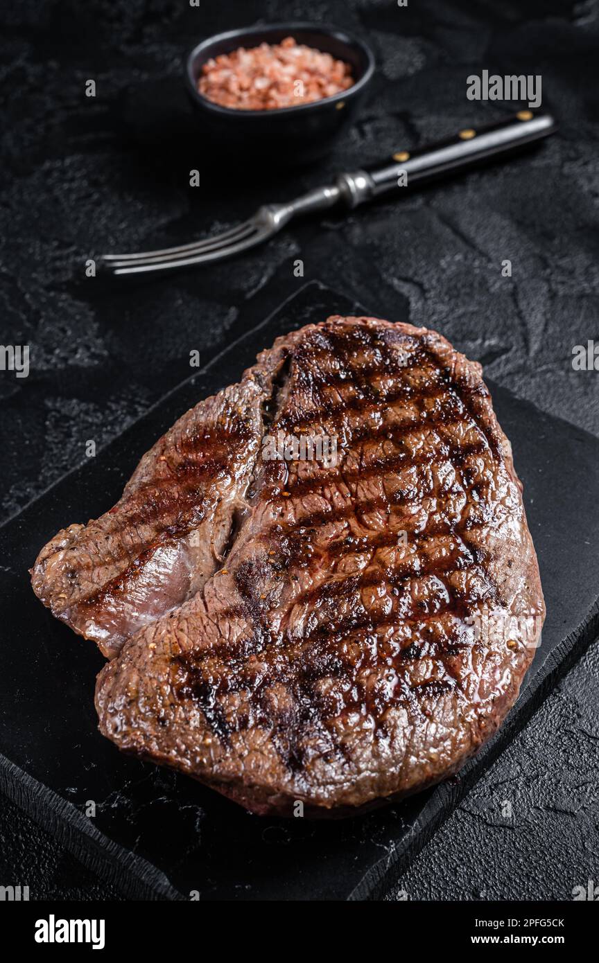 Grilled top sirloin or rump steak on a marble board. Black background ...