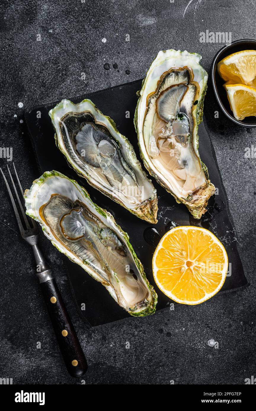 Seafood Brassiere, open Oysters with lemon. Black background. Top view ...