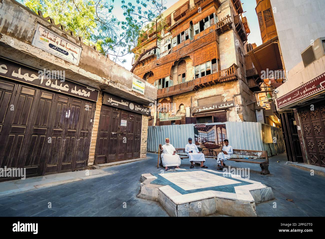 Portrait of Saudi men sitting on benches and relaxing in front of old ...
