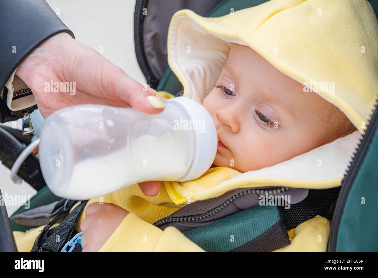Baby boy contentedly drinks milk from a bottle Stock Photo - Alamy