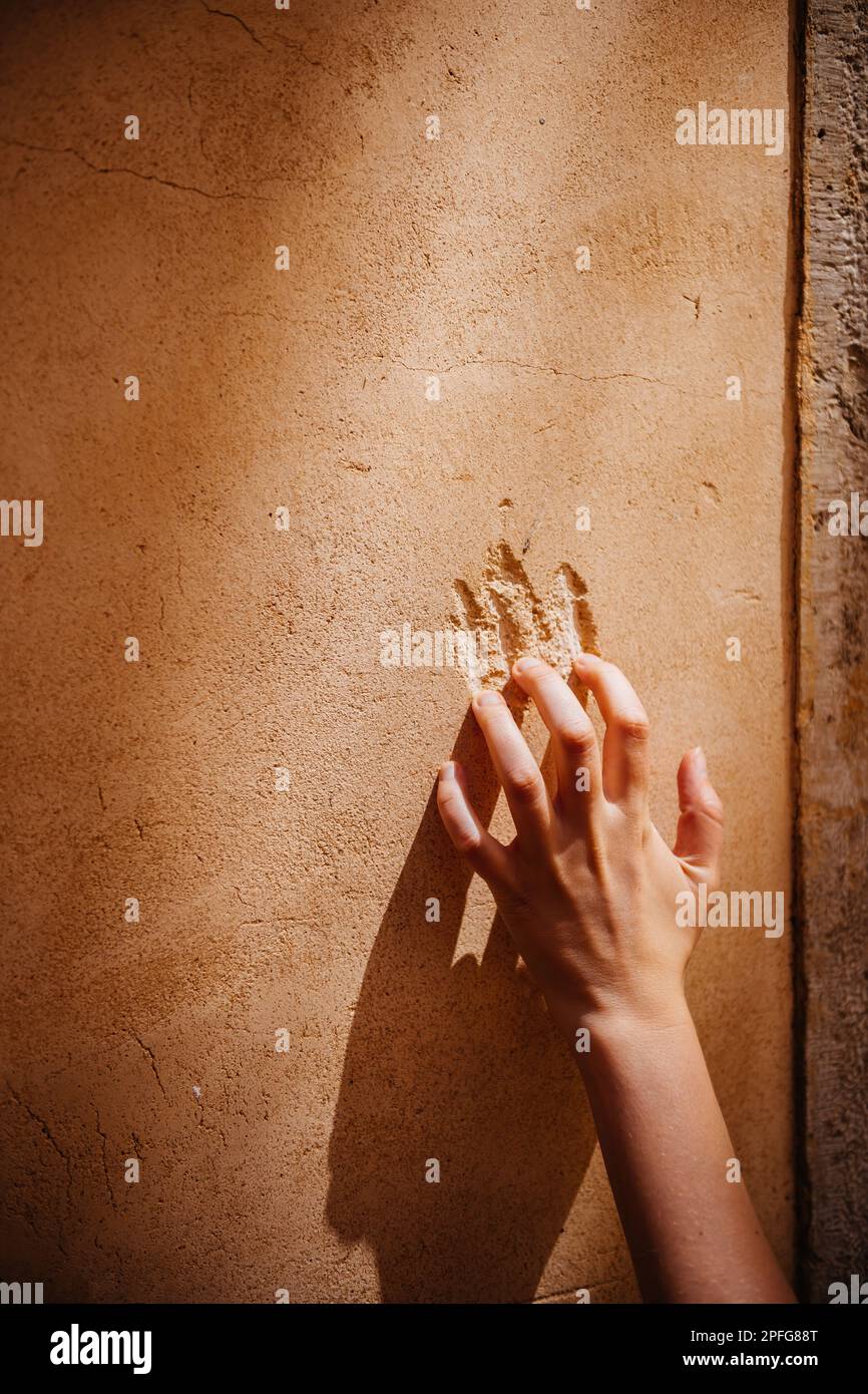 A close-up of a persons hand, scratching the wall in an attempt to ...