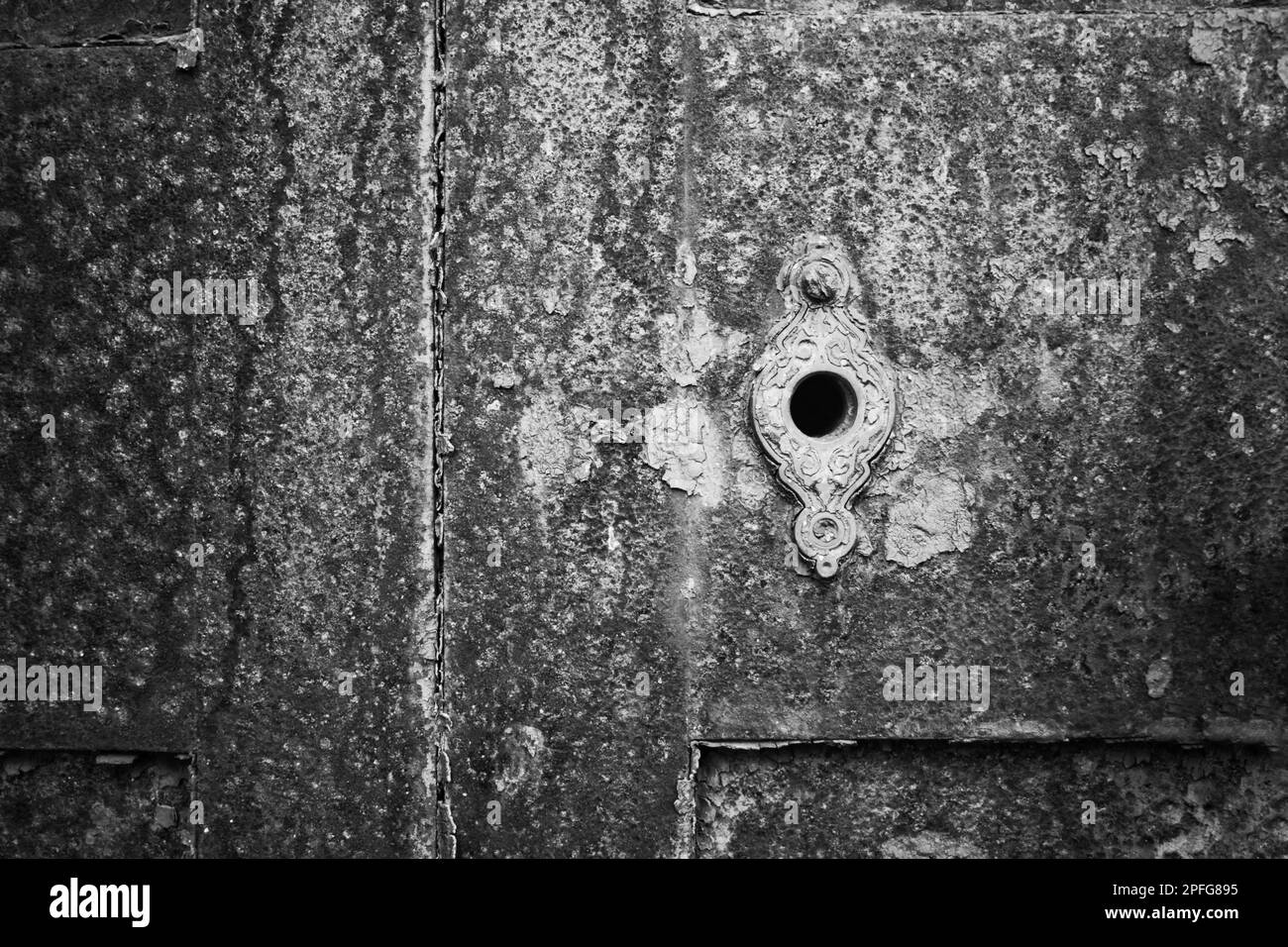 An old worn and weathered rusty wall with a medieval keyhole in a black ...