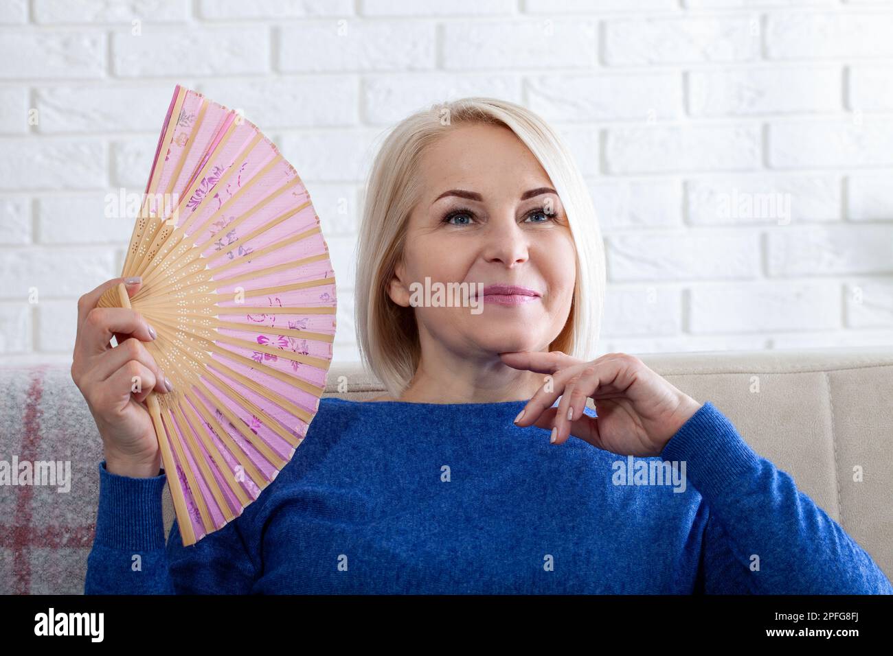 Woman waving a fan pleased with the coolness. Woman enjoying air flow ...