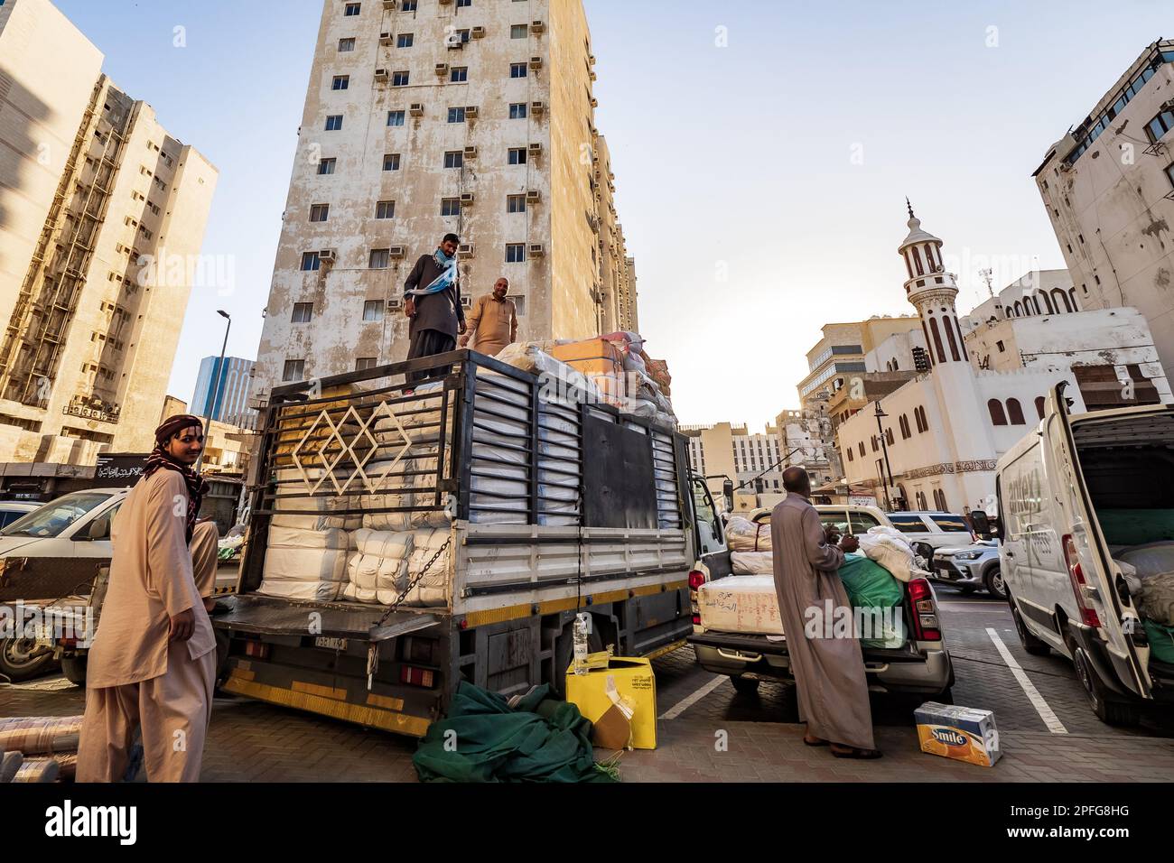 View of local men loading purchased bales of textile goods onto a truck ...