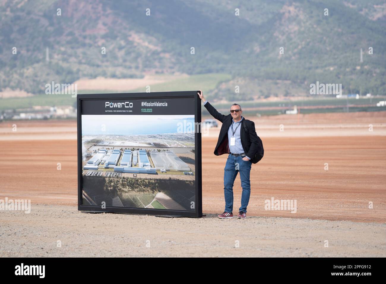 A man leaning on a sign announcing the start of construction of the ...