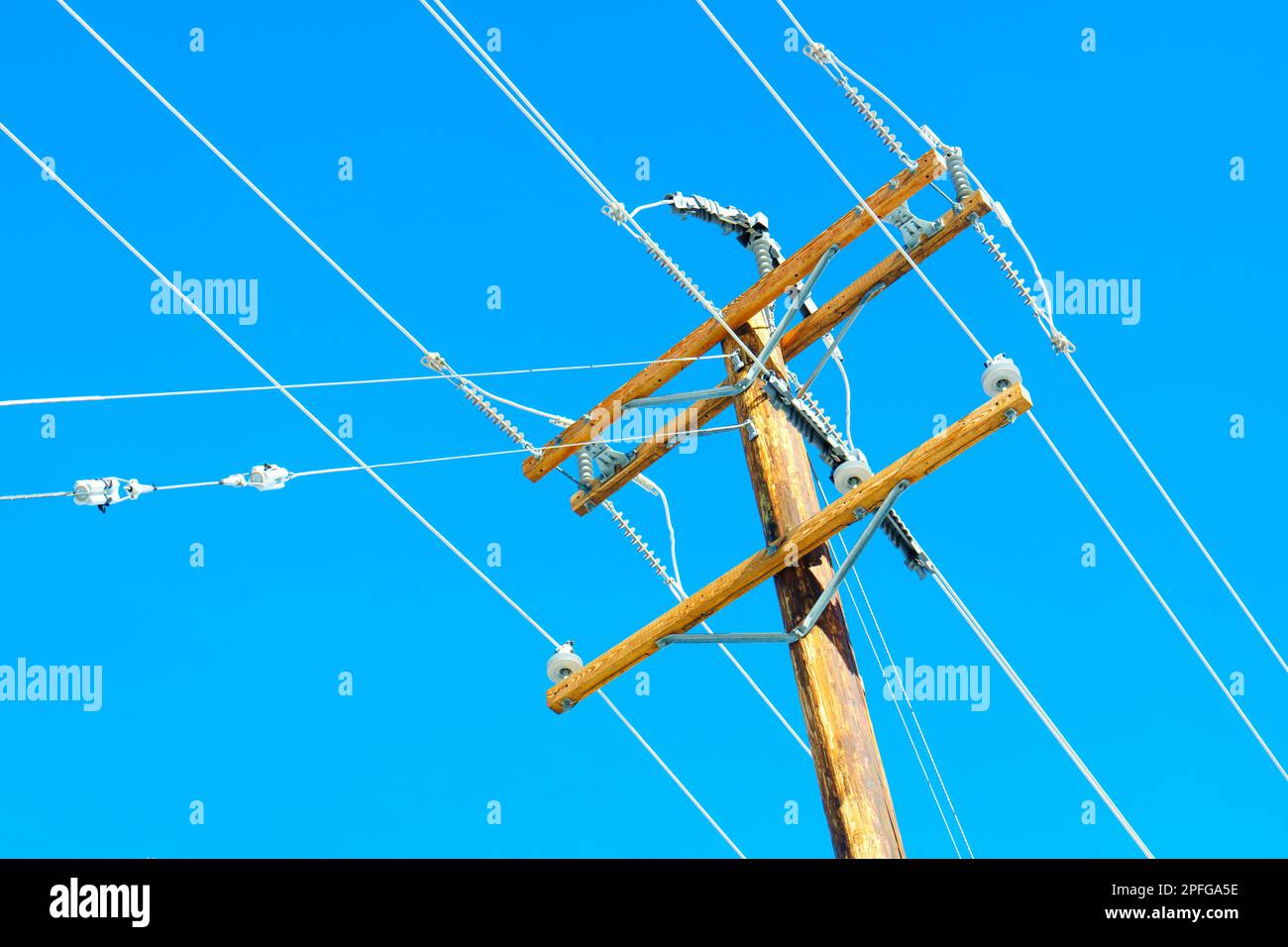 Low-angle view of a wooden power pole and wires against a clear sky ...