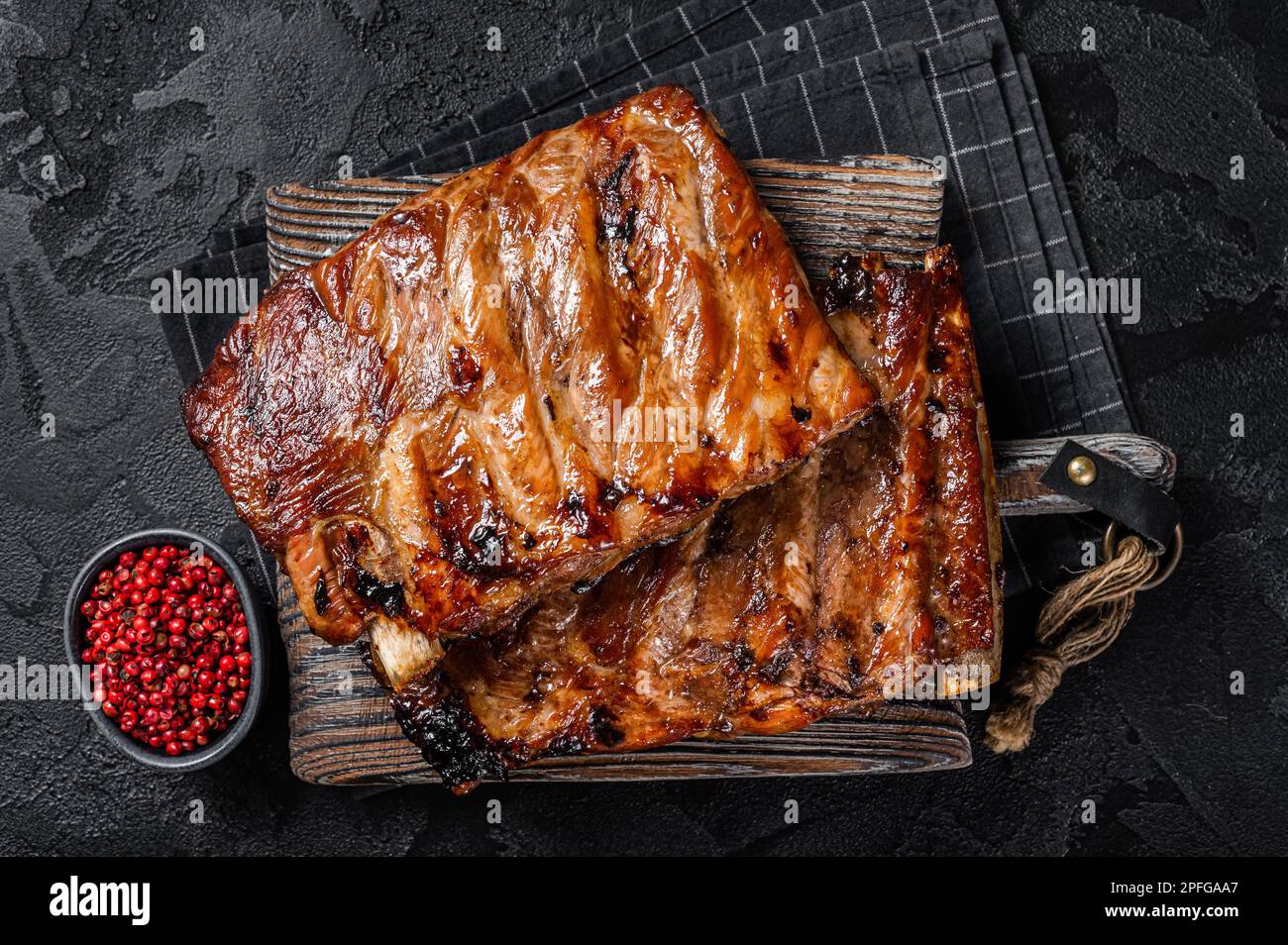 Stack of grilled pork ribs in BBQ sauce on a chopping board. Black ...