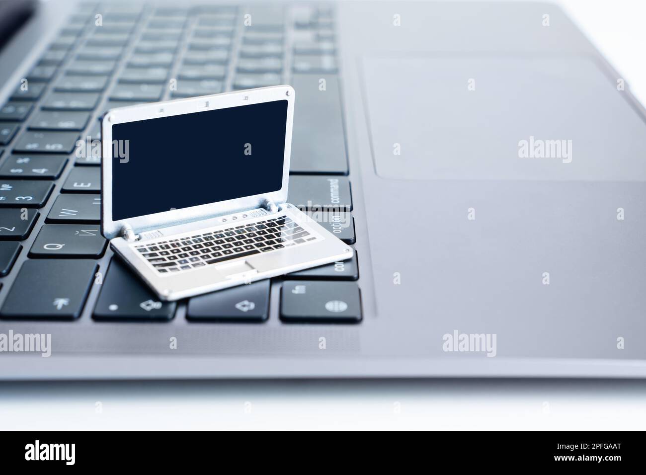 Miniature laptop positioned on a full-sized laptop keyboard. Creative ...