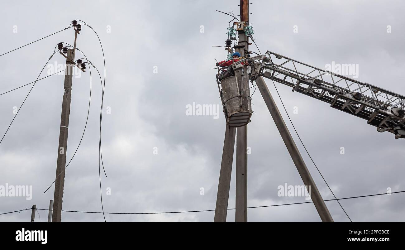 A team of electricians is seen working to restore a power line in ...