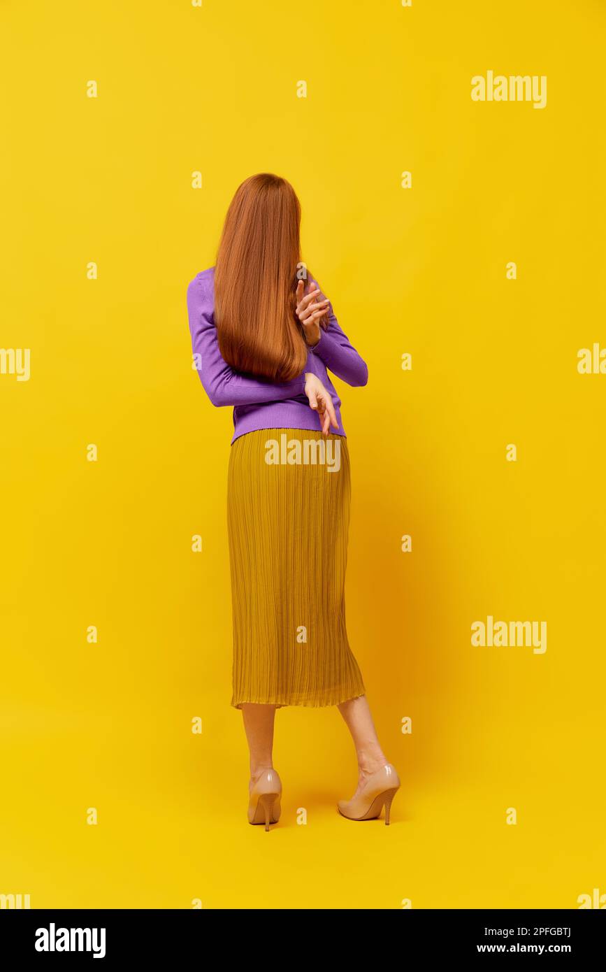 Faceless portrait of slim woman with long straight red hair wearing ...