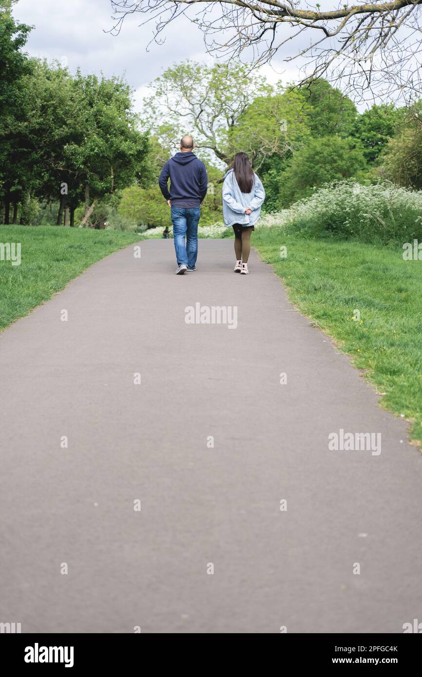 Vertical photo of a multicultural couple walking on a footpath in ...