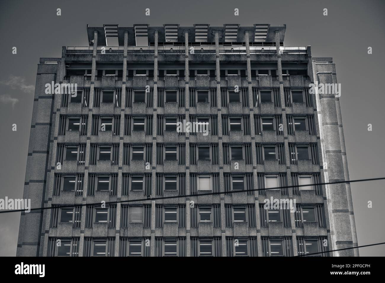 A grayscale shot of a modern building with square windows in the ...