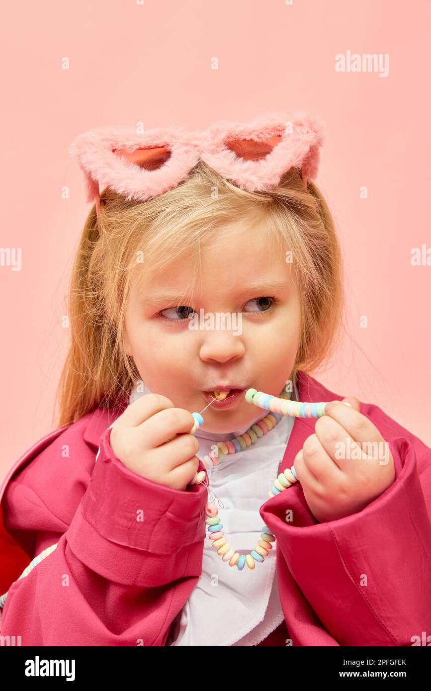 Portrait of sytlish sweet tooth girl wearing sunglasses, eating sweets ...