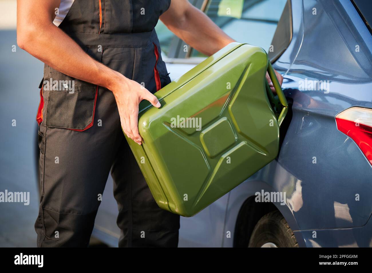 Stalled car filling with gasoline by professional worker. Young man ...