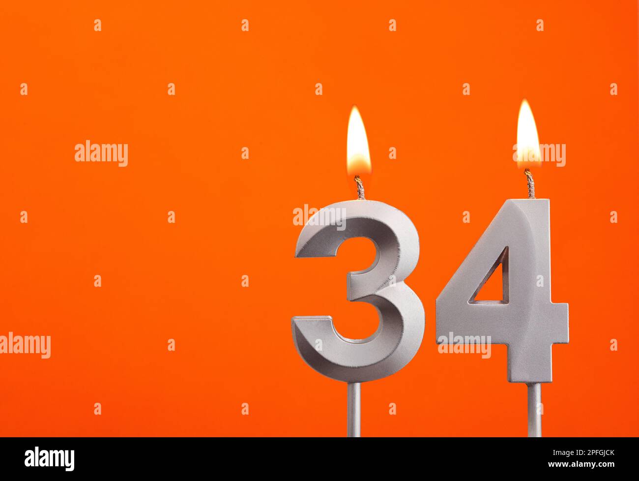 Candle number 34 - Birthday in orange background Stock Photo - Alamy