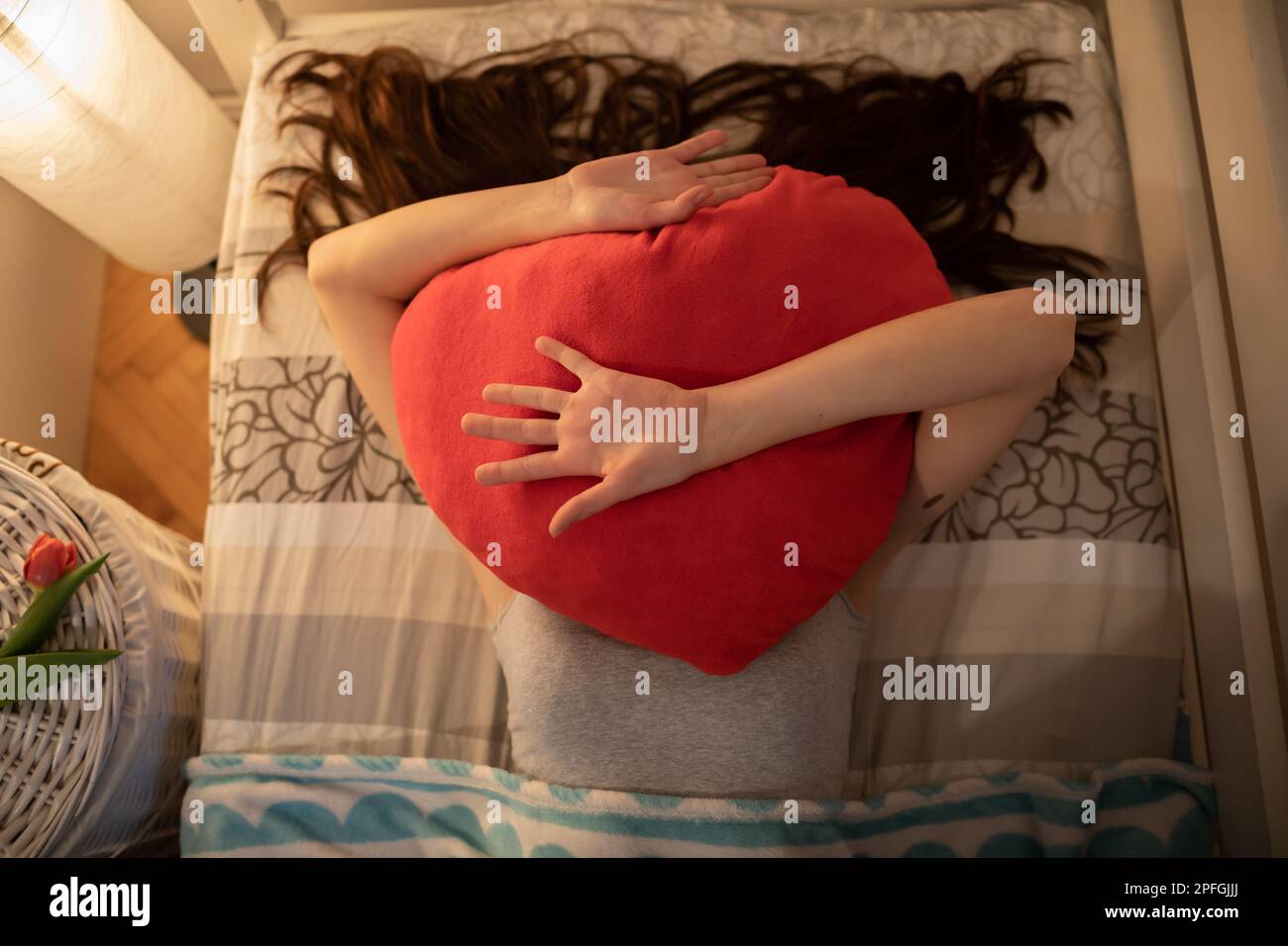 The red heart-shaped pillow is lying on the girls face Stock Photo - Alamy