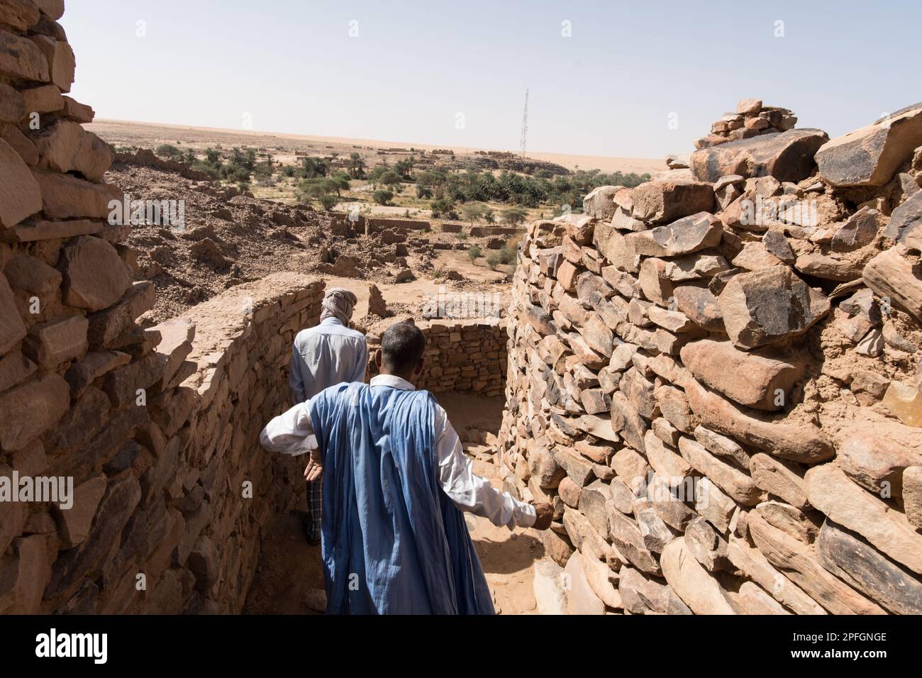 Two locals in traditional clothing walk amidst the weathered ruins of ...