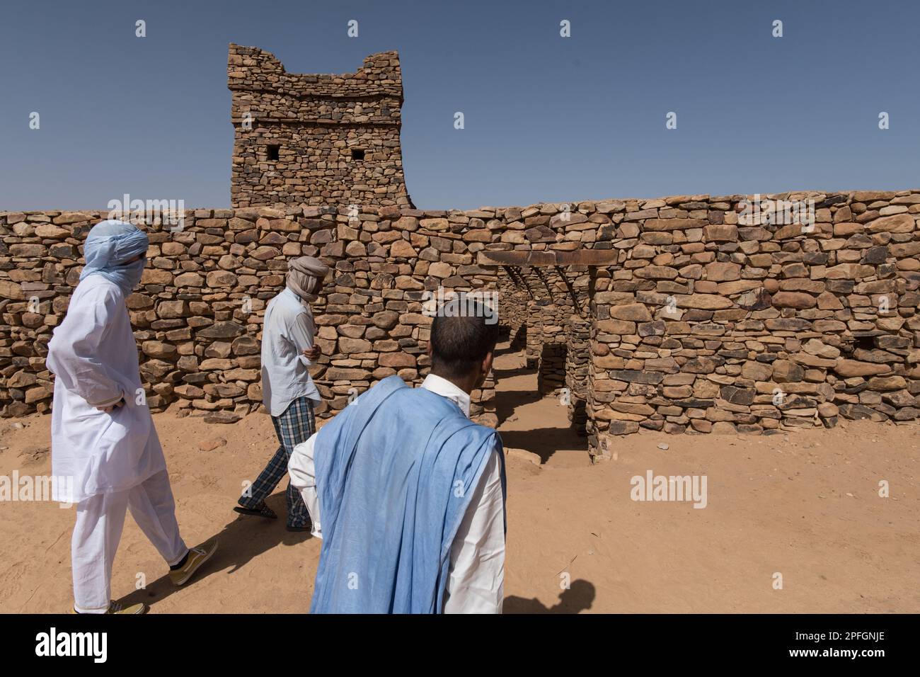 Two locals in traditional clothing walk amidst the weathered ruins of ...