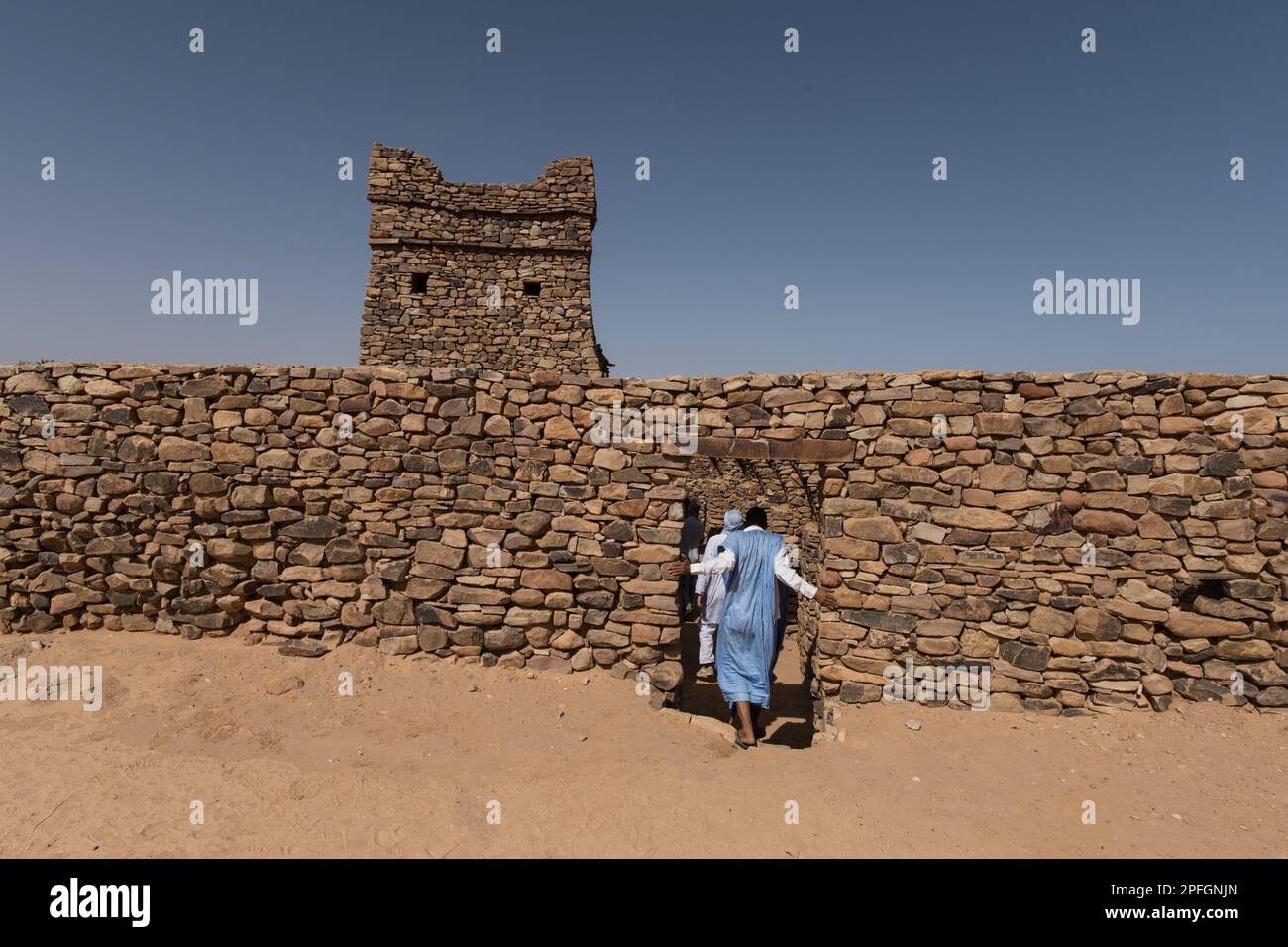 Two locals in traditional clothing walk amidst the weathered ruins of ...