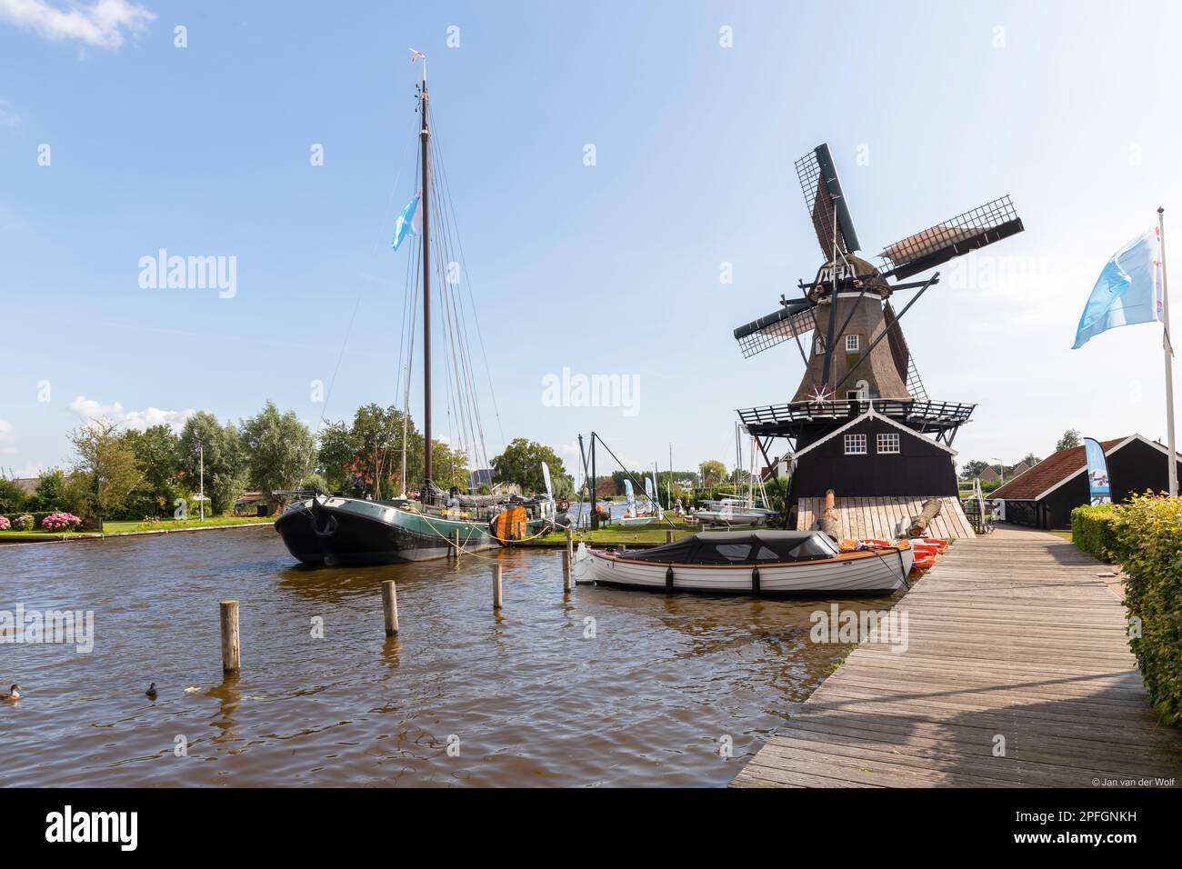 Windmill and a historic sailboat along the water near the village of ...