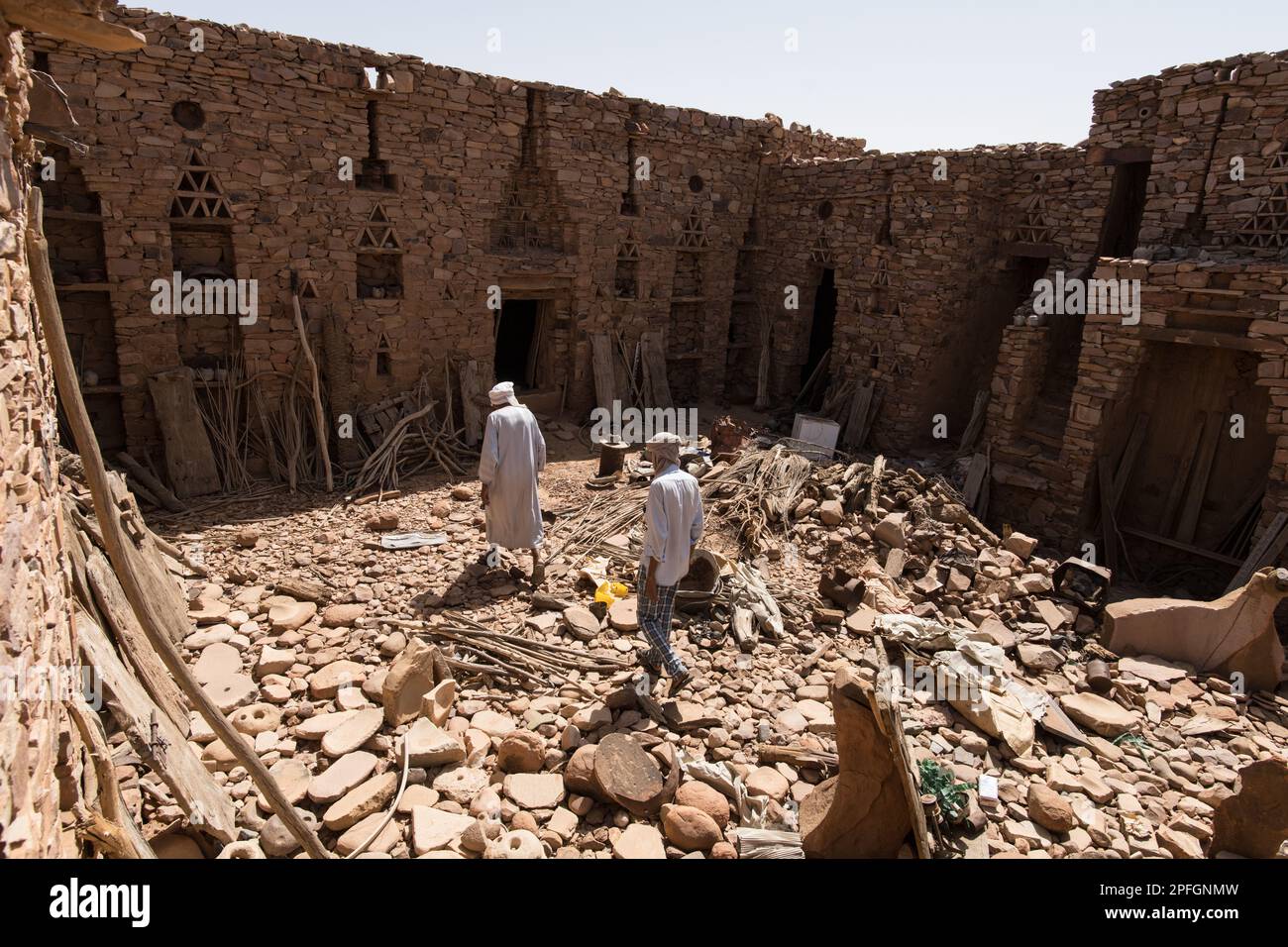 Two locals in traditional clothing walk amidst the weathered ruins of ...