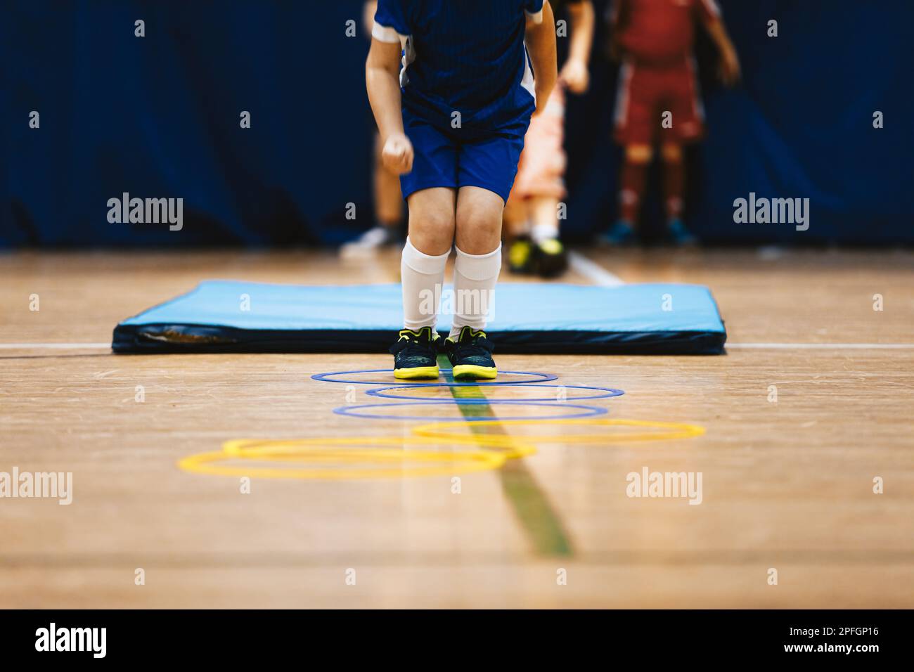 Group of children in school age jumping over obstacles at indoor ...