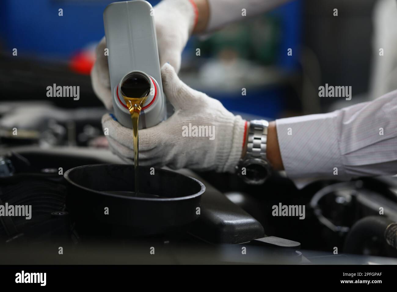 Auto mechanic pour engine oil into car engine closeup Stock Photo - Alamy