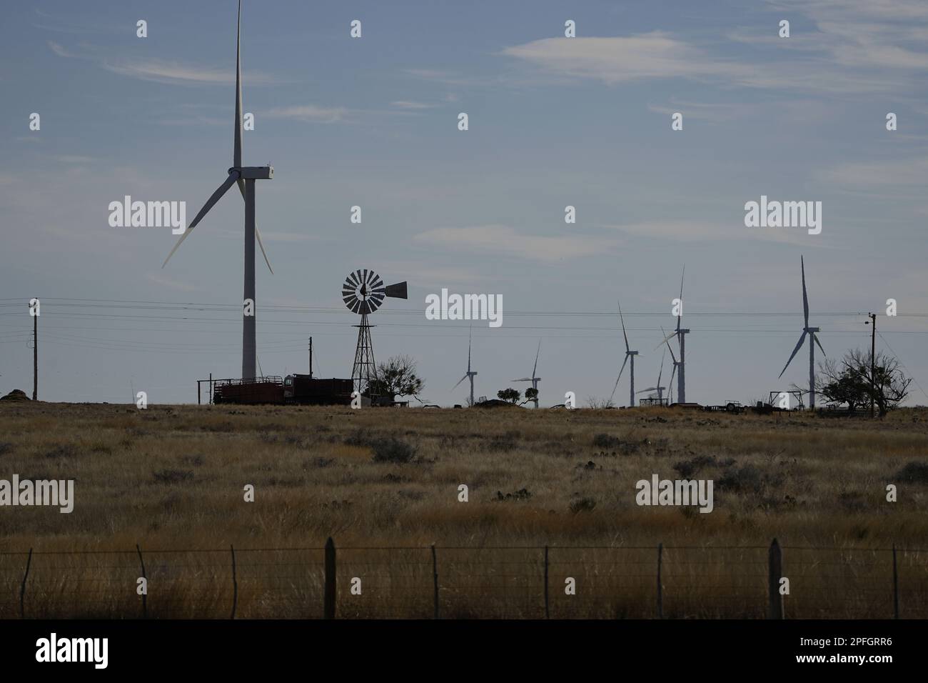 Wind turbines tower over a traditional windmill on a ranch near Del Rio ...