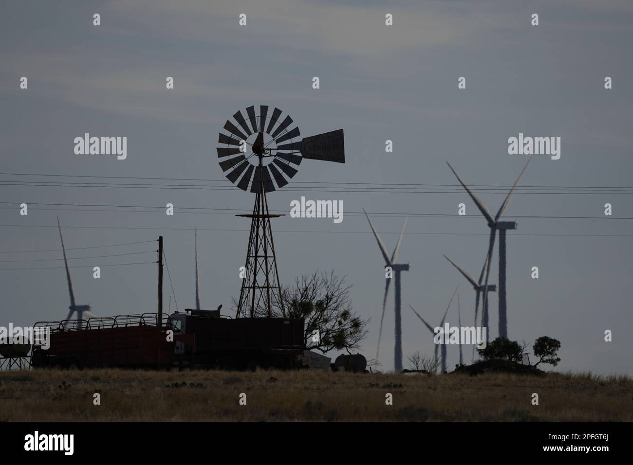 Wind turbines tower over a traditional windmill on a ranch near Del Rio ...