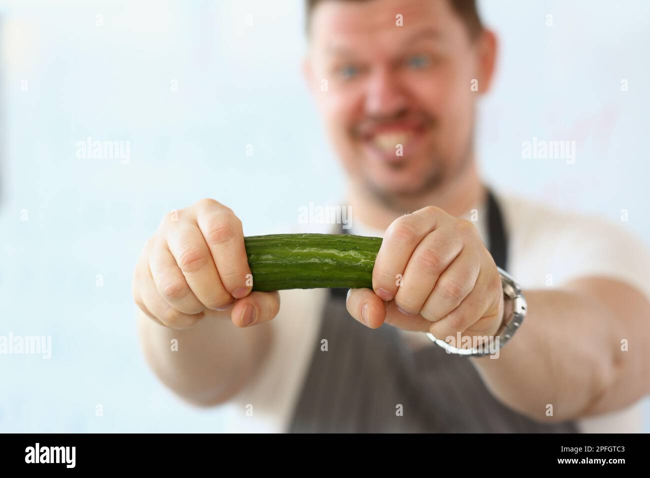 Emotional male cook with cucumber vegetable in hand Stock Photo - Alamy