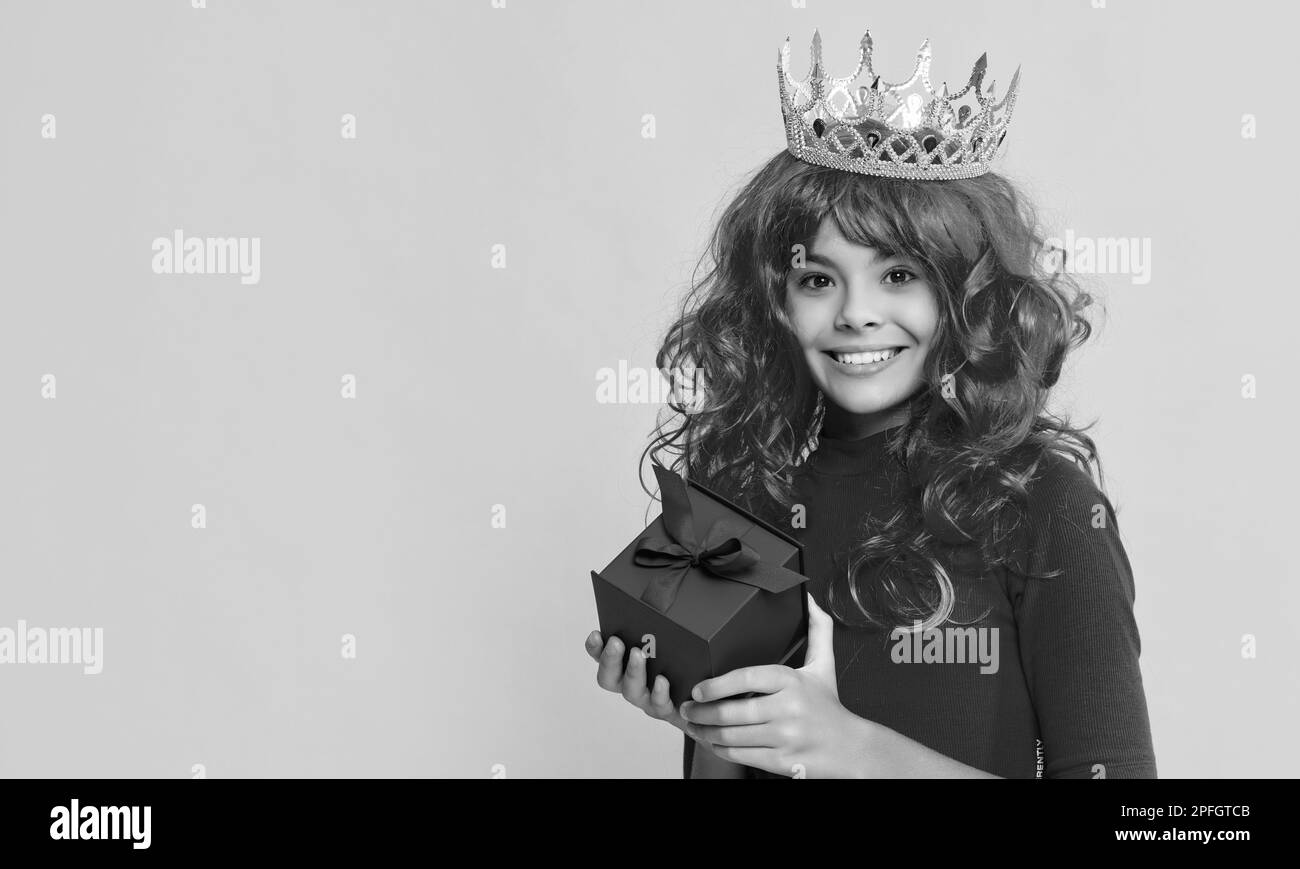 positive girl in crown with present box on yellow background Stock ...