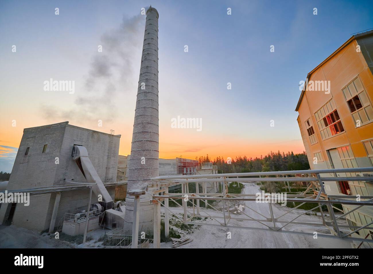 High smoking pipe at limestone production plant in evening Stock Photo ...