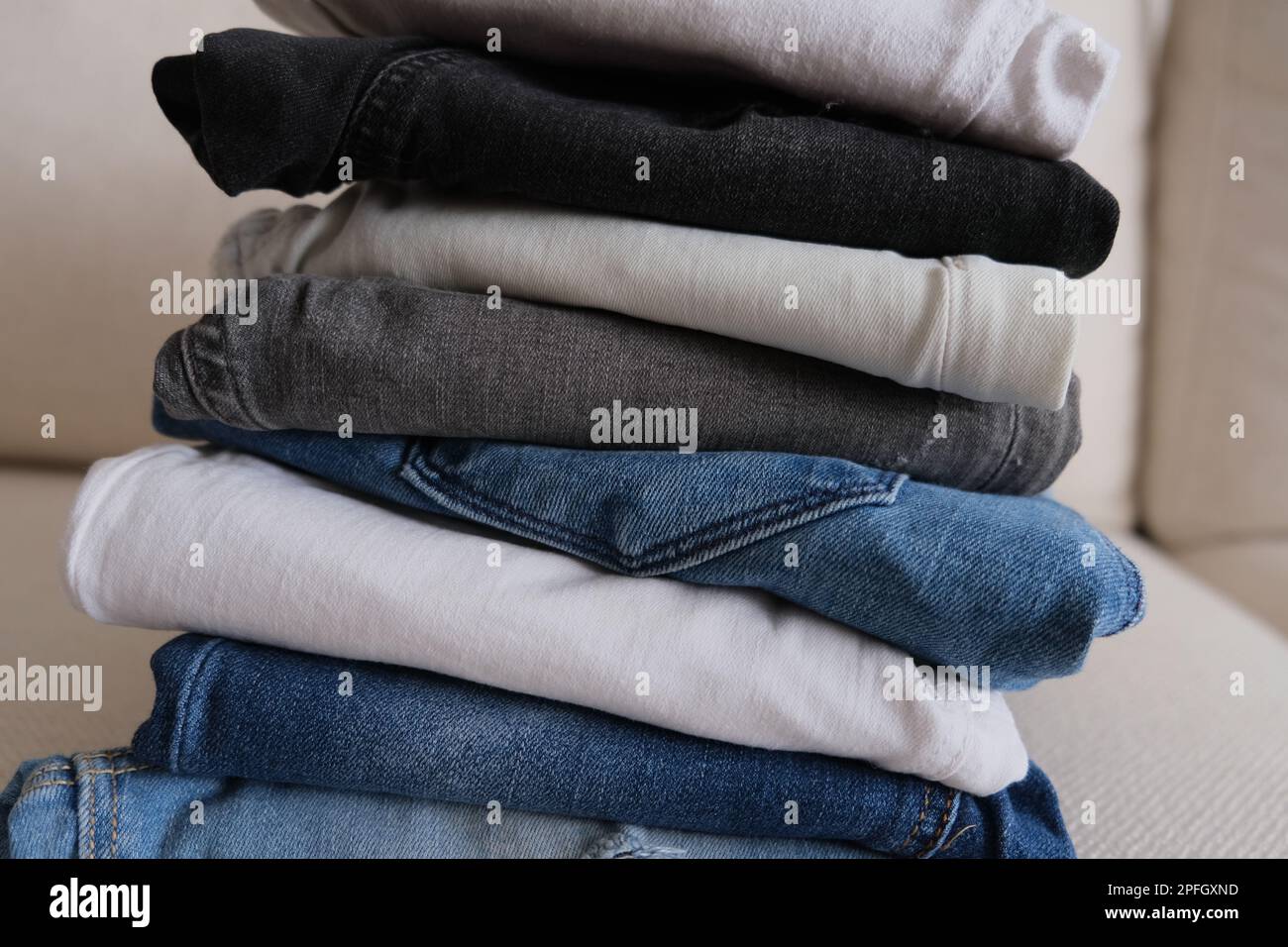 Denim pants, folded and stacked denim pants on a white sofa, denim ...