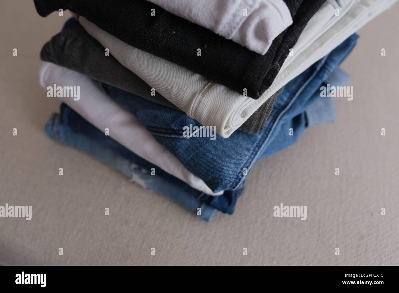 Denim fabric, folded and stacked denim pants on a white sofa, denim ...