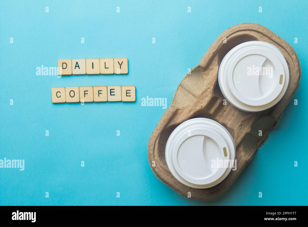 A cardboard with 2 paper coffee cups and lids with a sign reading Daily ...