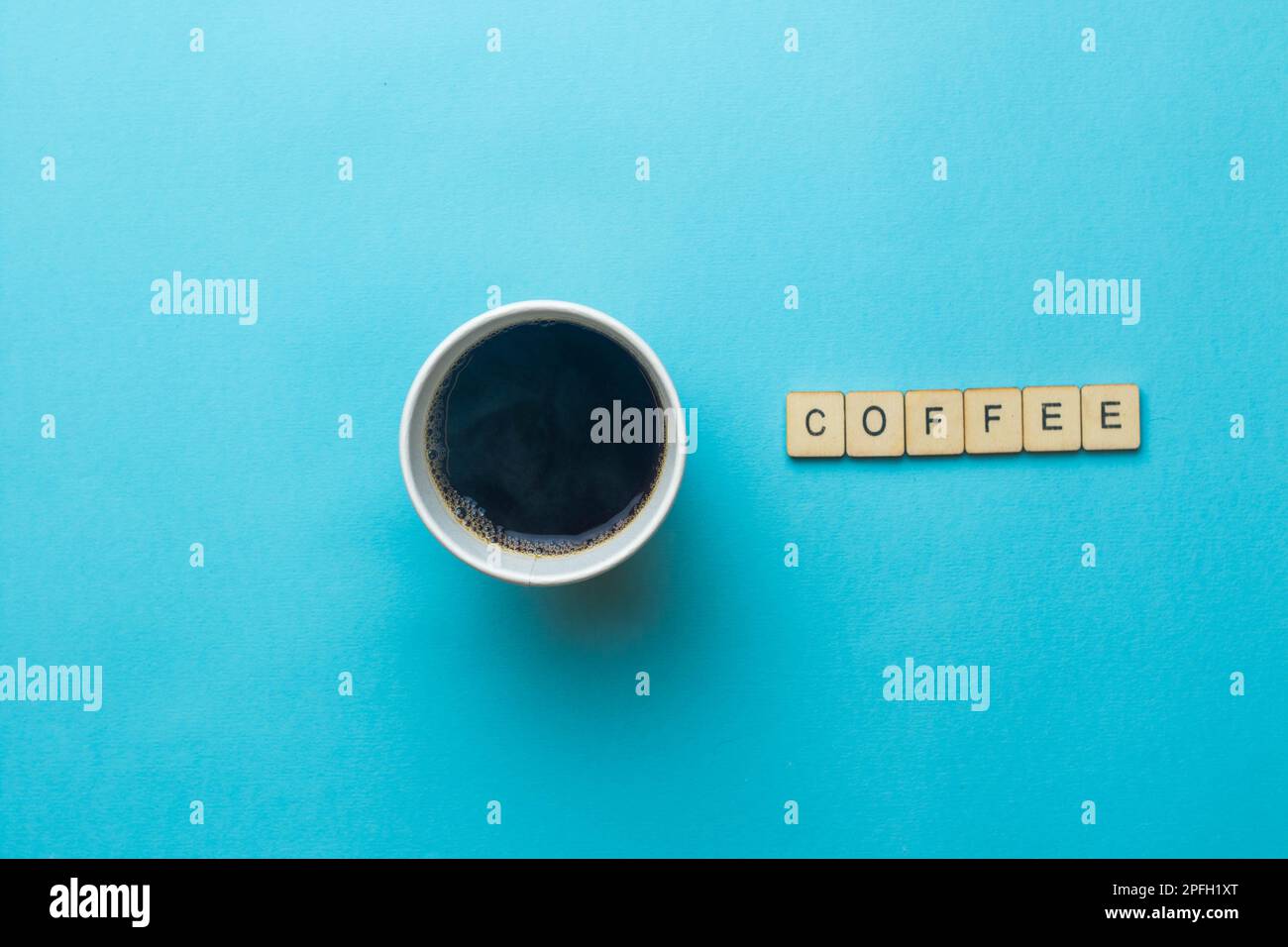 An open paper cup of black cofffee on a blue background with a sign ...