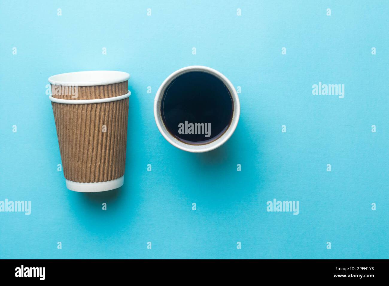 An open cup of black coffee next to a stack of paper coffee cups Stock ...