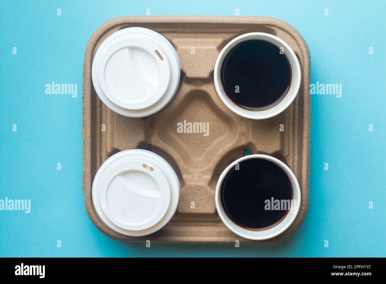 Two open and two with lids cups of black coffee on a cardboard tray ...