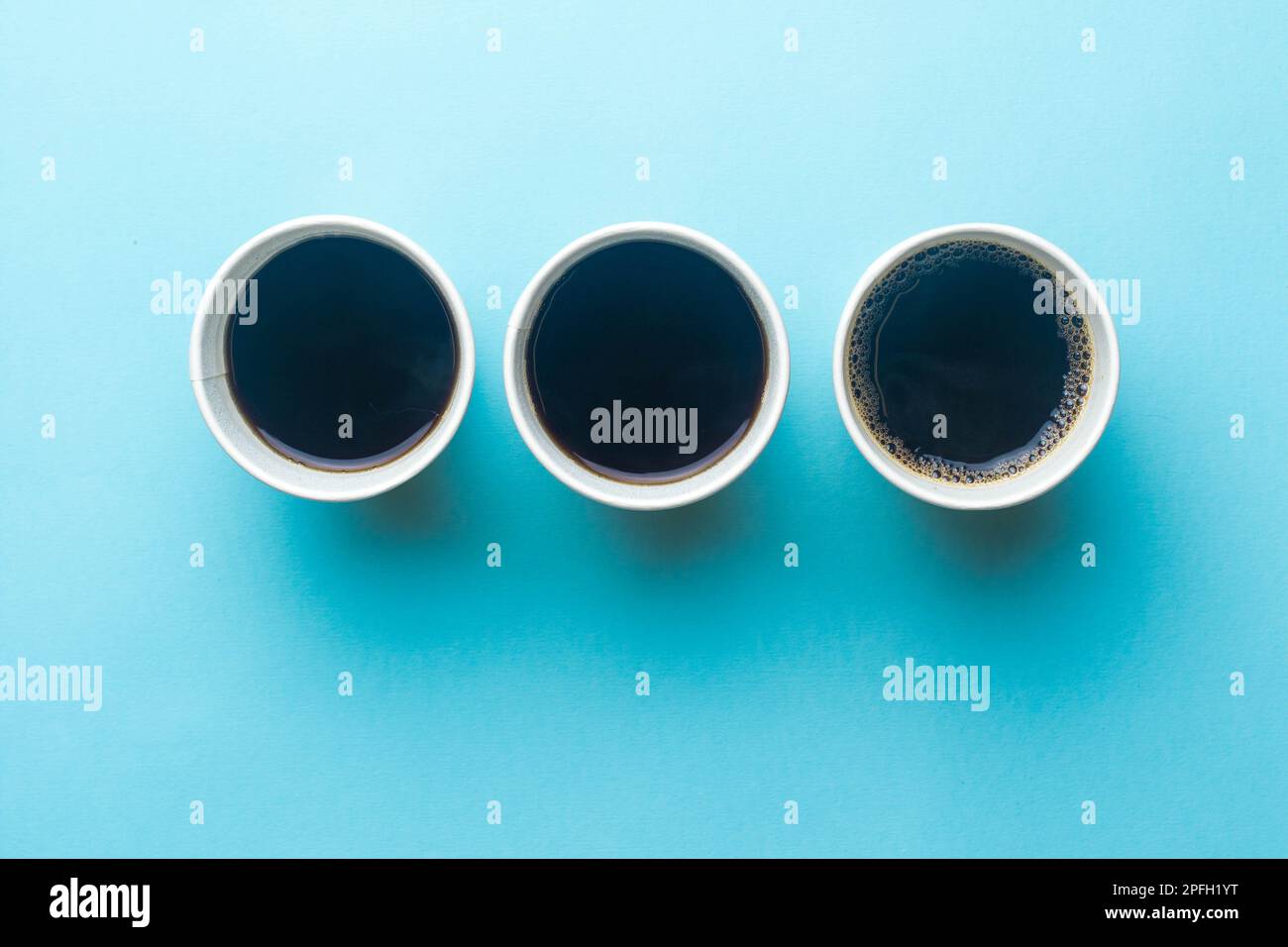 3 open cups of black coffee on a blue black ground Stock Photo - Alamy