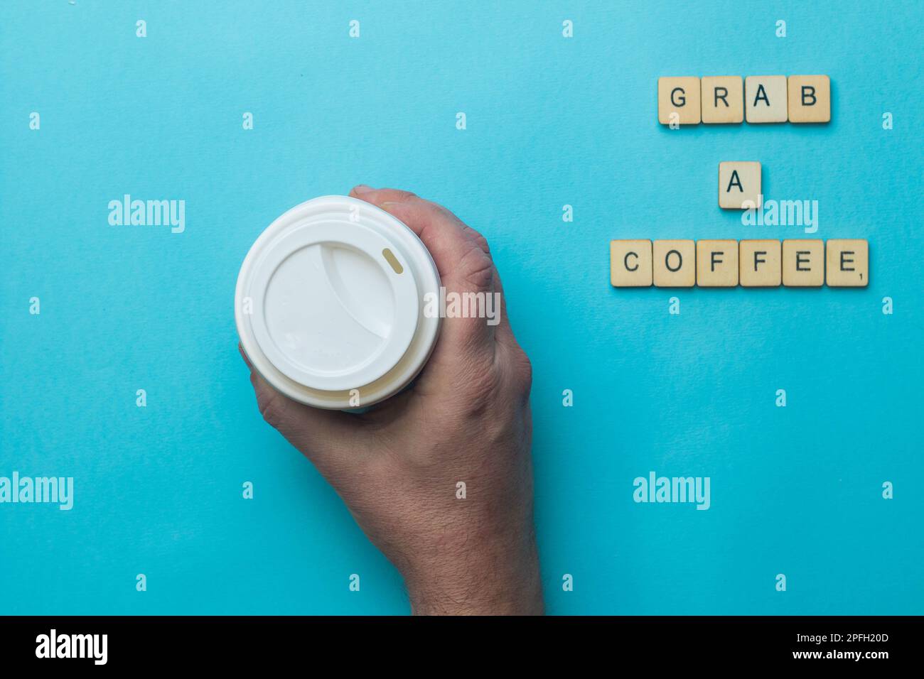 A paper coffee cup and lid held by a hand on a blue background with a ...