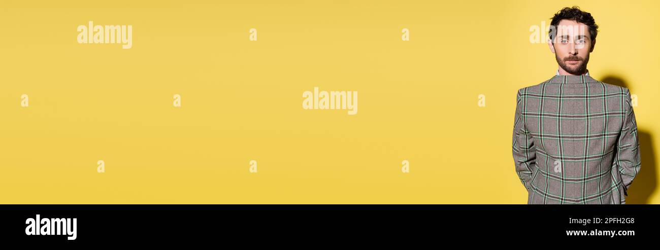 Brunette model wearing jacket backwards on yellow background, banner ...