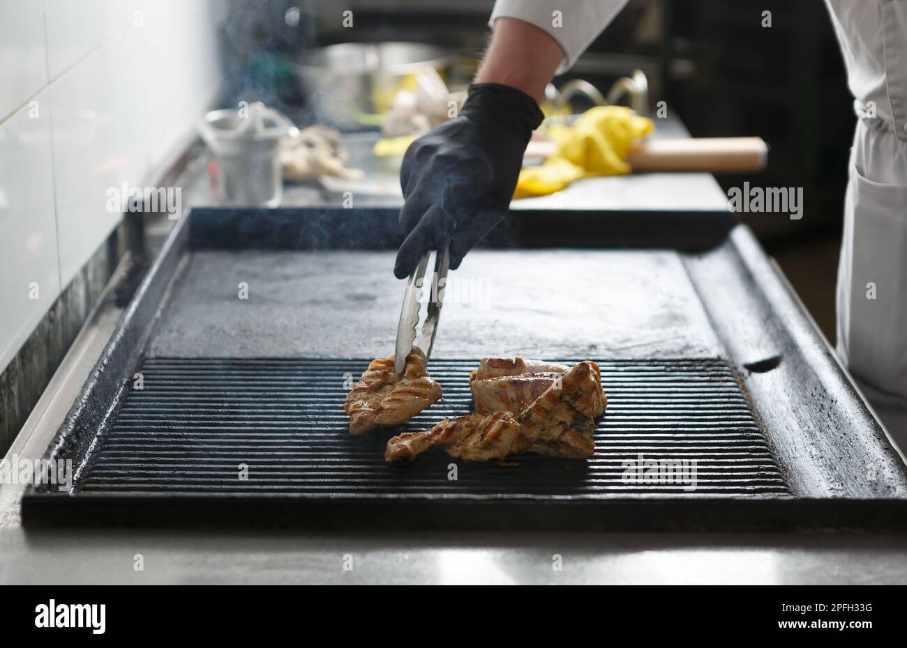 Cook cooking chicken meat on grill. Chef turning the poultry fillet ...