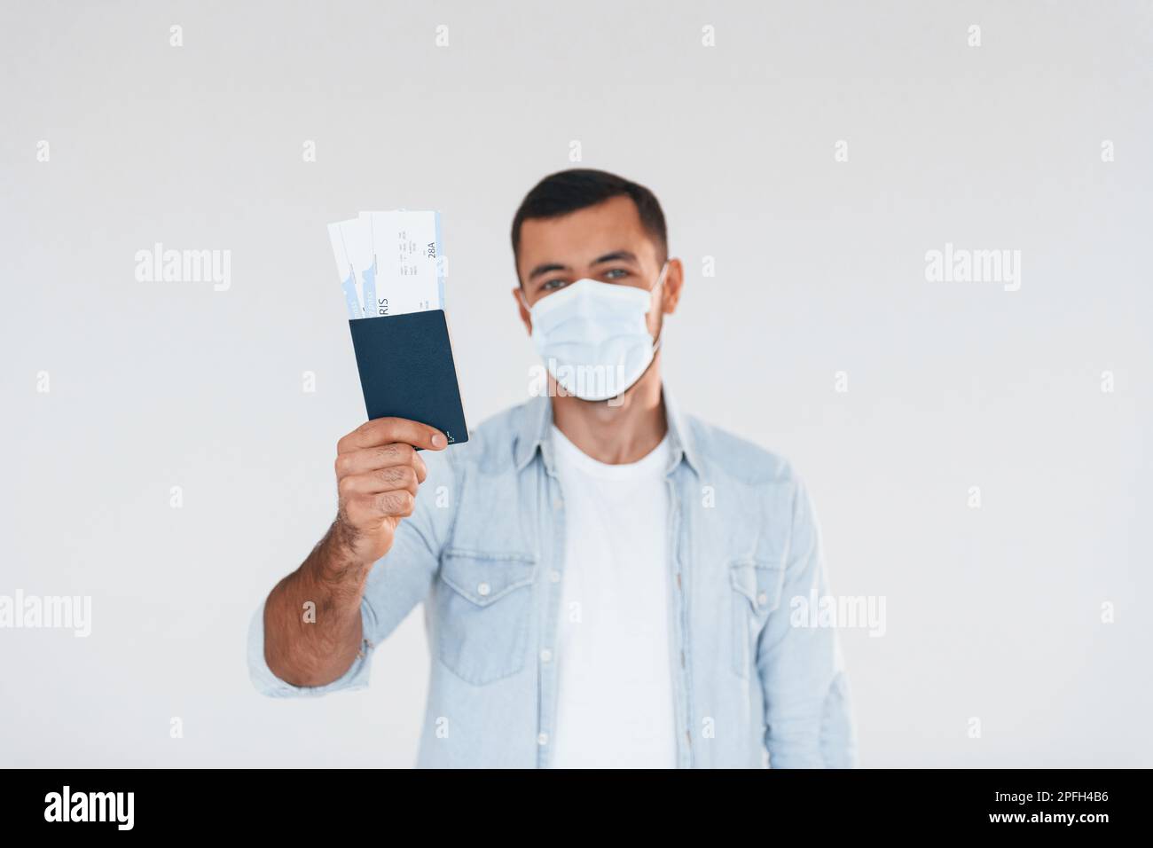 Tourist with ticket. Young handsome man standing indoors against white ...