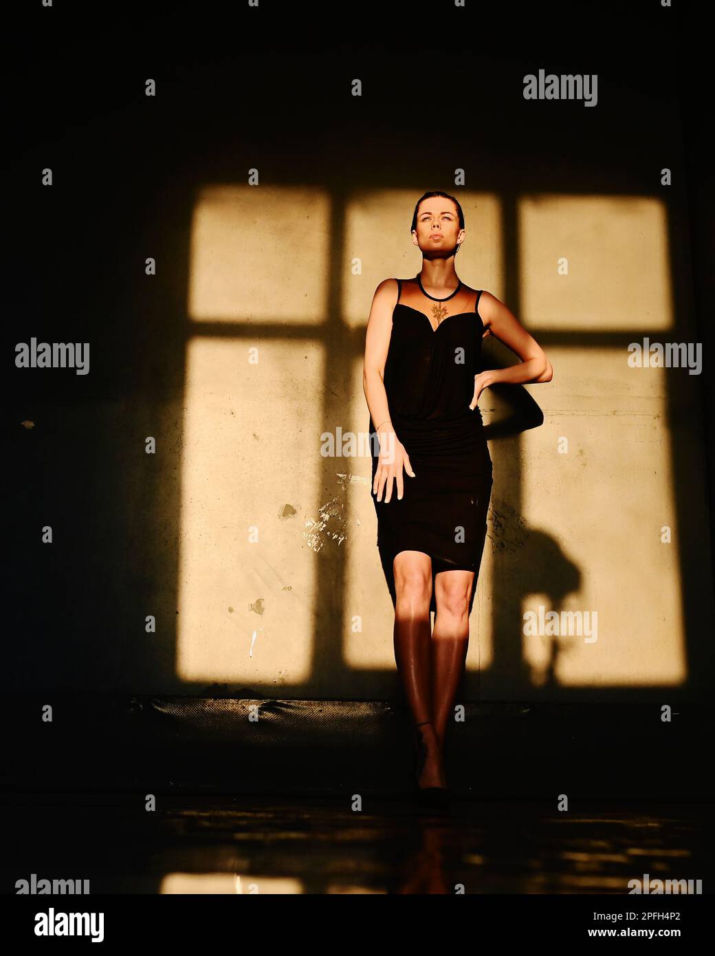 Water splash. A girl in black dress under the drops water. Wet clothes ...