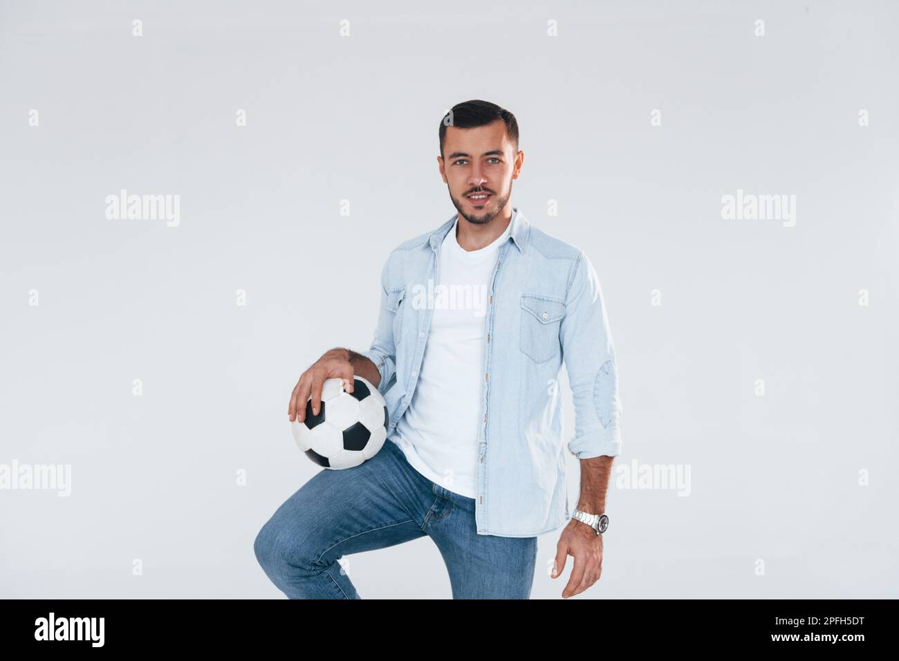 Football fan with soccer ball. Young handsome man standing indoors ...
